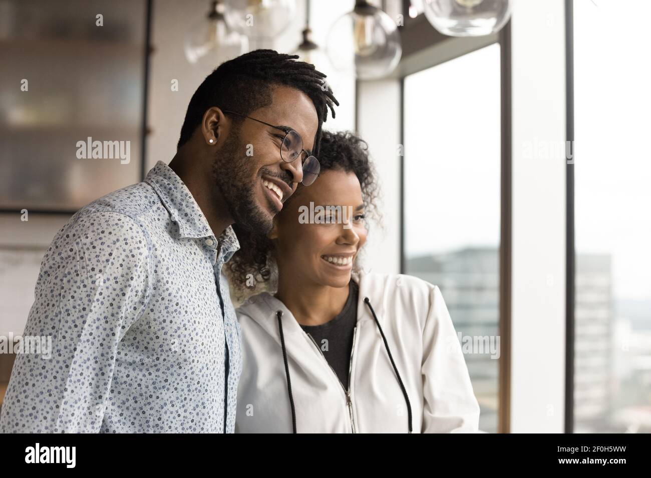 Close up smiling African American couple hugging, visualizing good ...