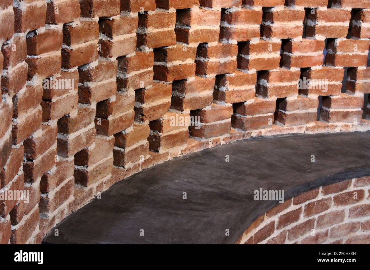 Curved red brick wall with concrete seat Stock Photo - Alamy