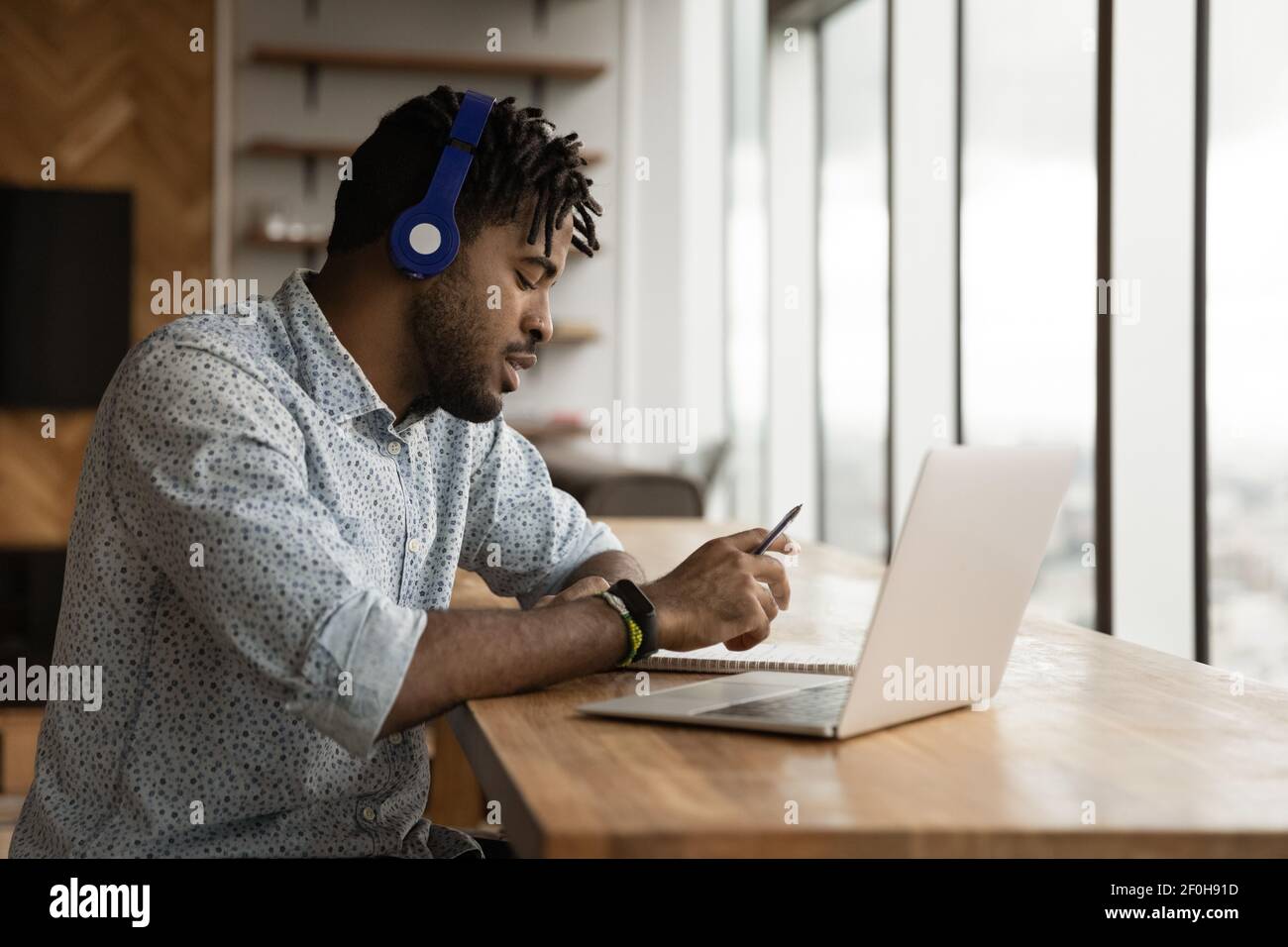 Side View African American Man Wearing Headphones Taking Notes Stock
