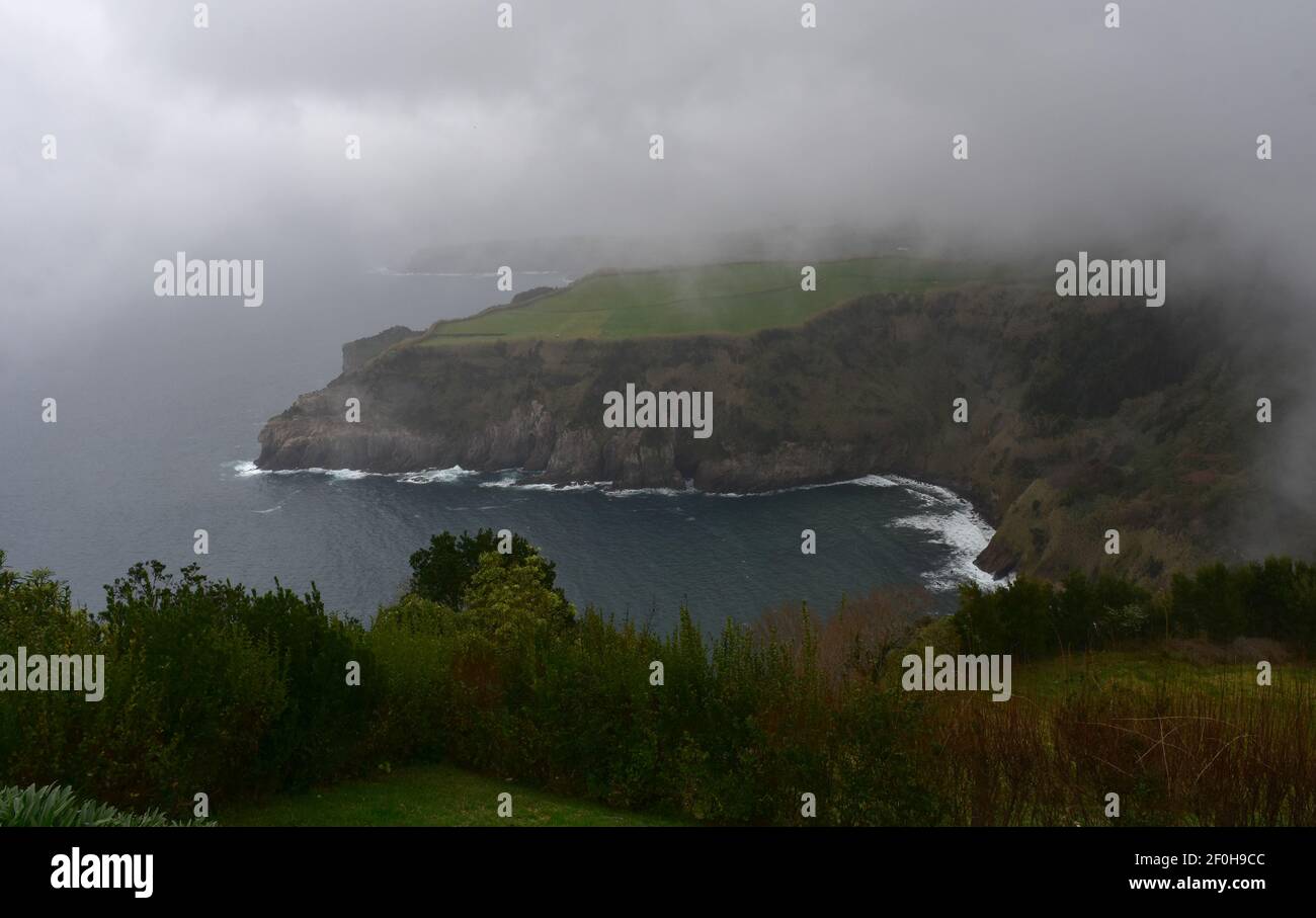 Wisps of fog and clouds hovering over the coastline of Sao Miguel Stock ...