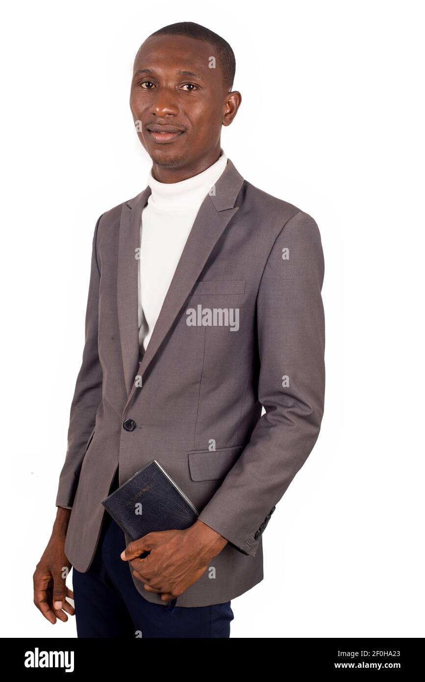young smiling pastor standing in jacket and holding a Bible on white ...