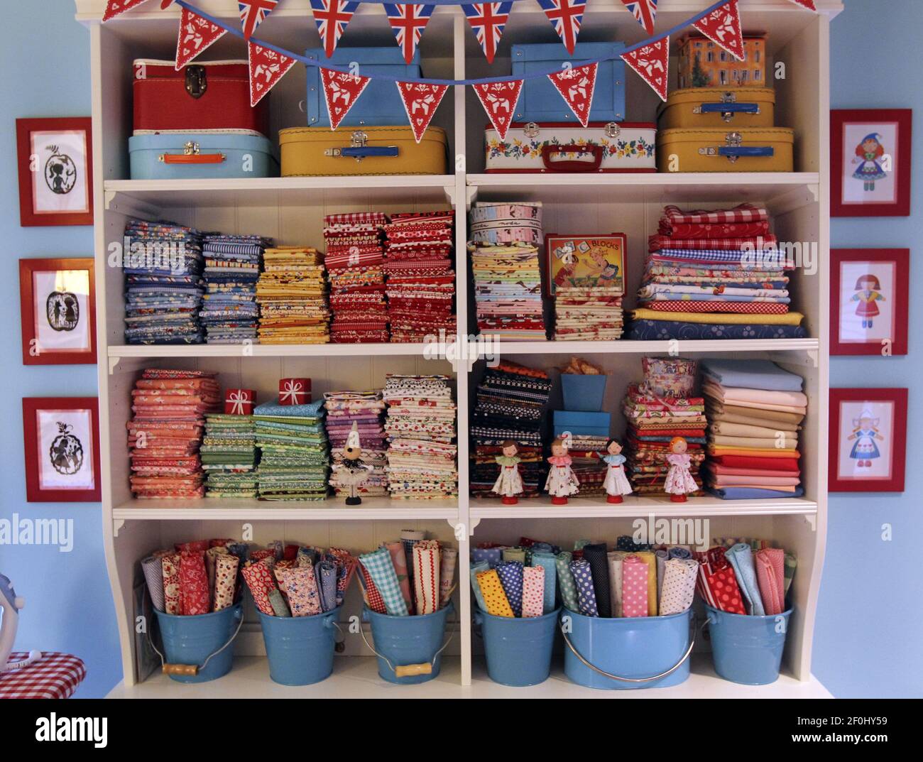 Shelves of fabrics are organized by color, and the rolls of fabric in ...