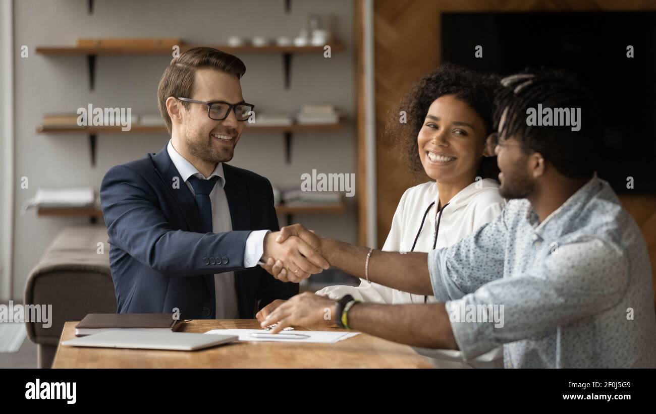Close up smiling manager and African American family shaking hands ...