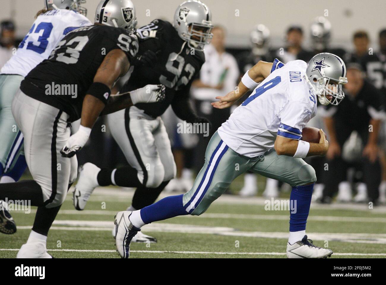 Dallas Cowboys quarterback Tony Romo (9) evades Tommy Kelly (93) and ...