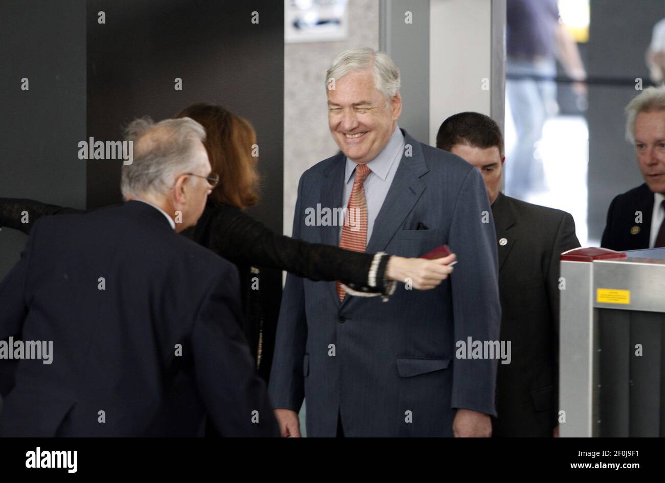 Conrad Black smiles as his wife Barbara Amiel goes through security ...