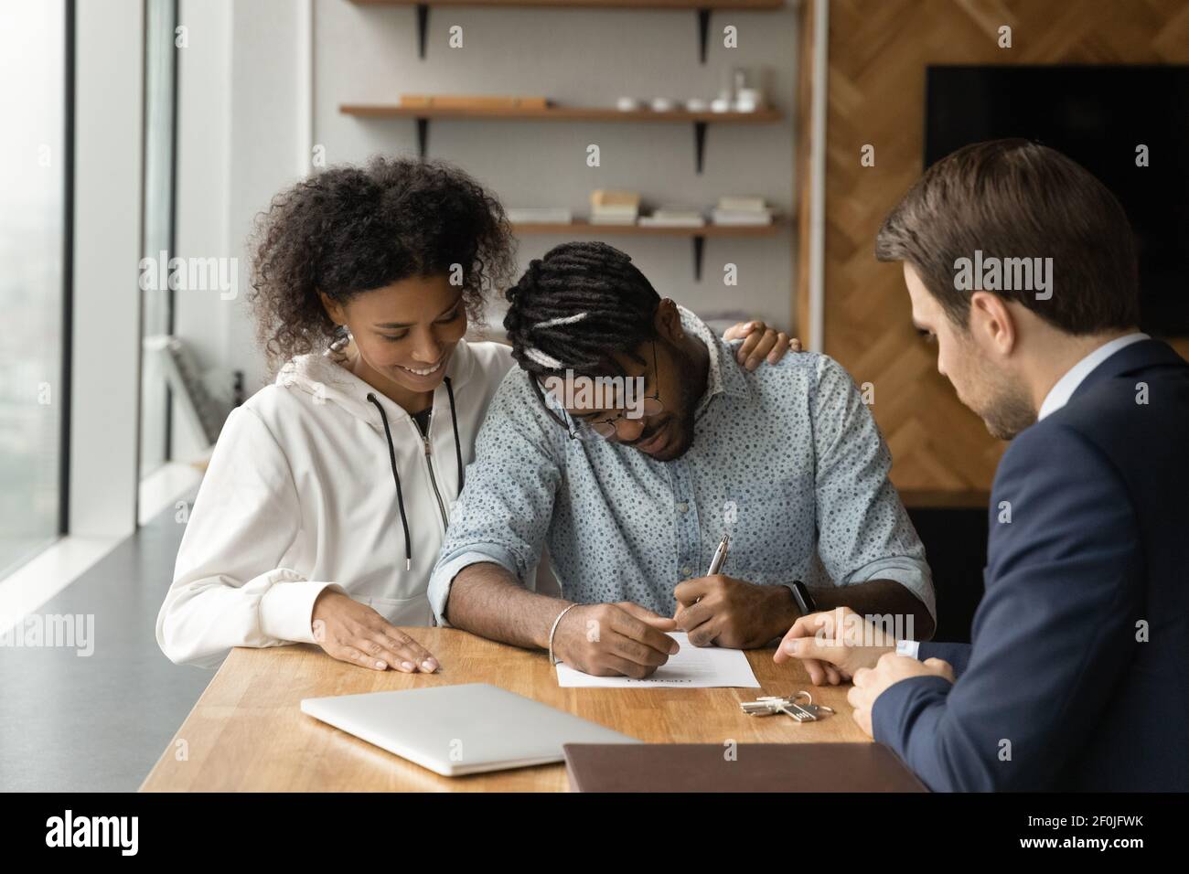 Close up happy African American family signing contract with manager ...