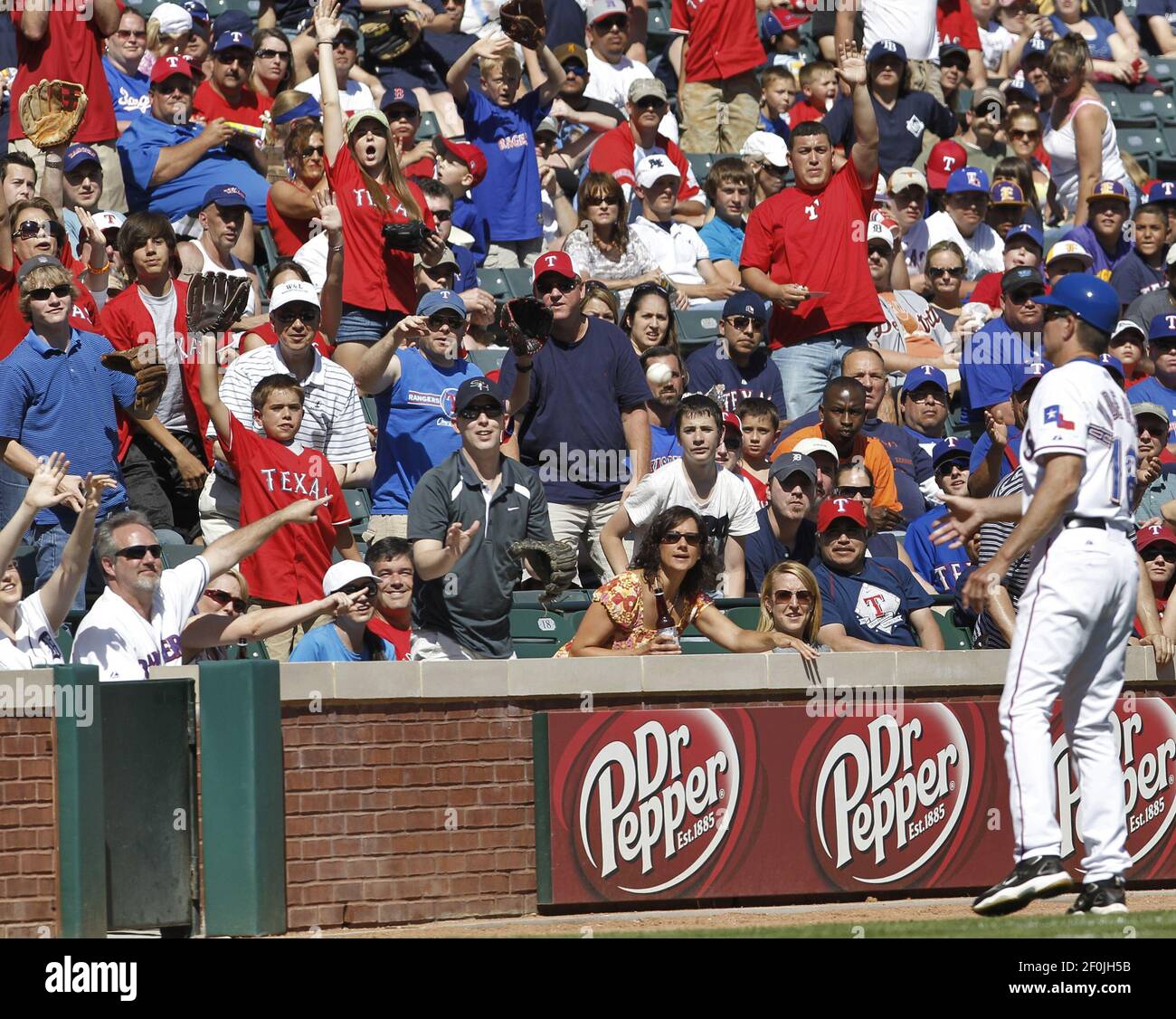 Texas Rangers third base coach Dave Anderson (16) tosses a foul ball to ...