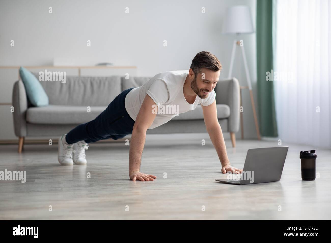 Happy middle-aged man in sportswear doing push-ups at home Stock Photo ...