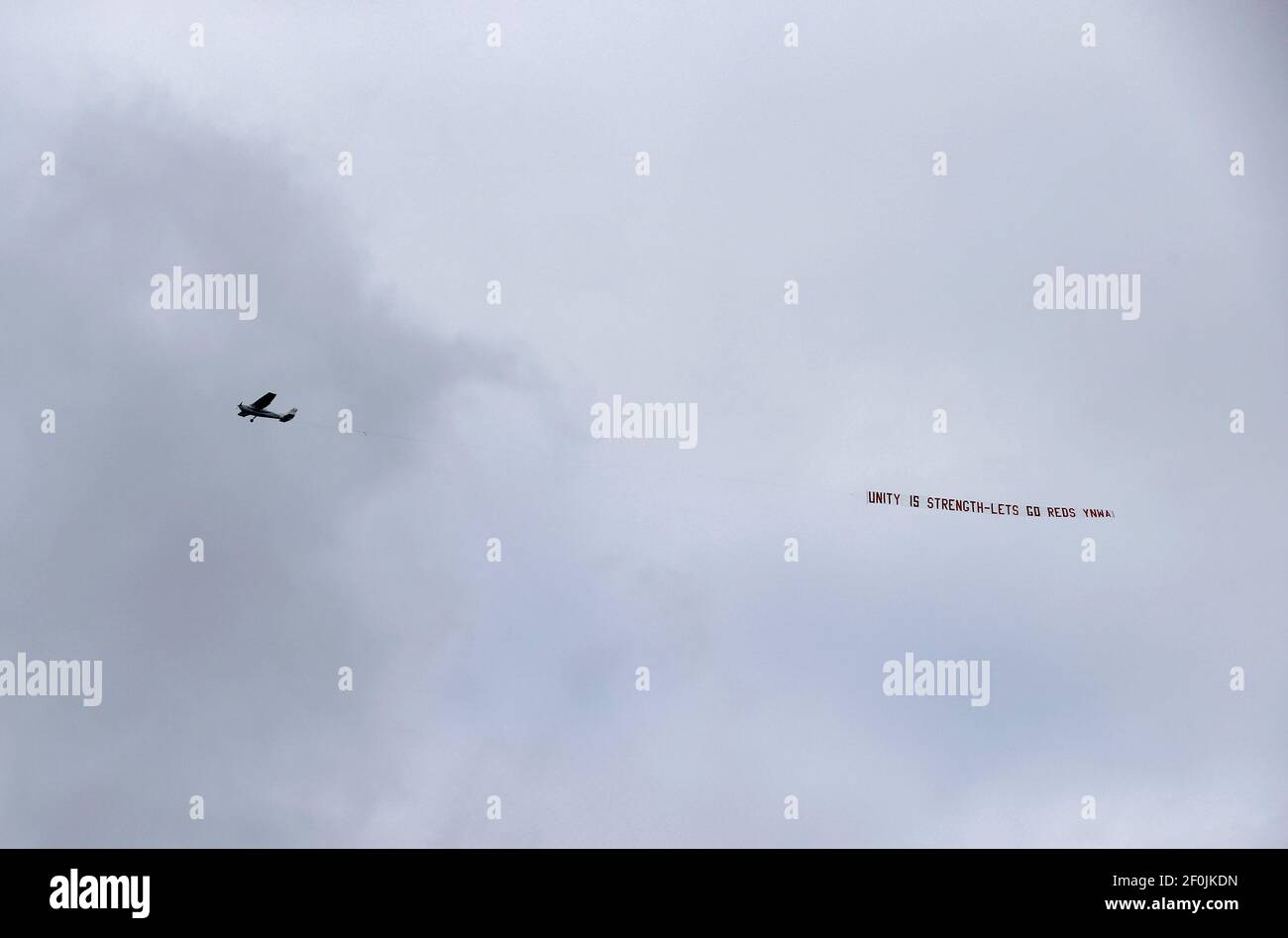 A plane flies overhead bearing the message "Unity Is Strength Go Reds ...