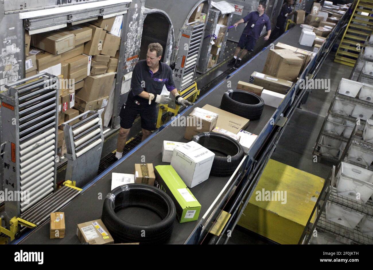 Randall Fisher unloads packages from containers onto a conveyor belt at ...