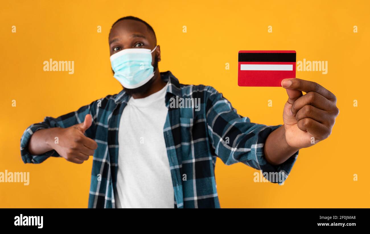 Black Man Wearing Mask Showing Credit Card Over Yellow Background Stock ...