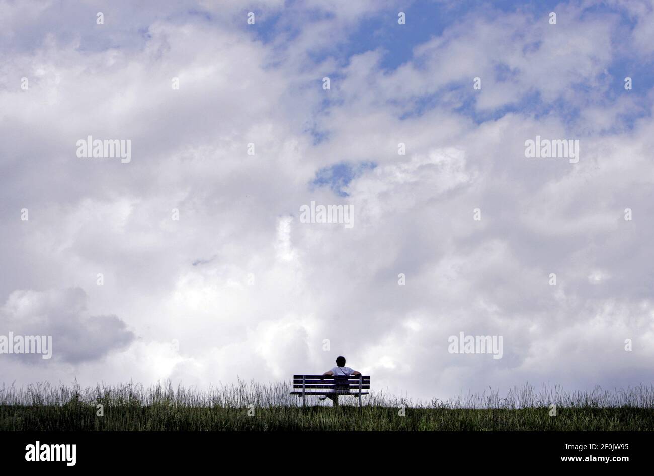 A walker takes a short break to sit on the bench and enjoy the nice ...