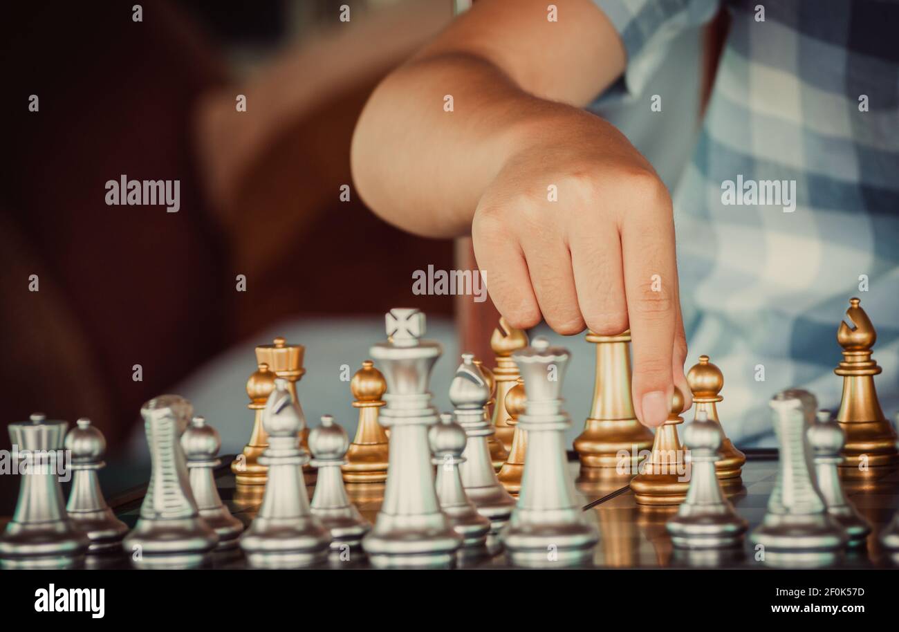 Close up of hand confident boy moving gold pawn chess to development in ...