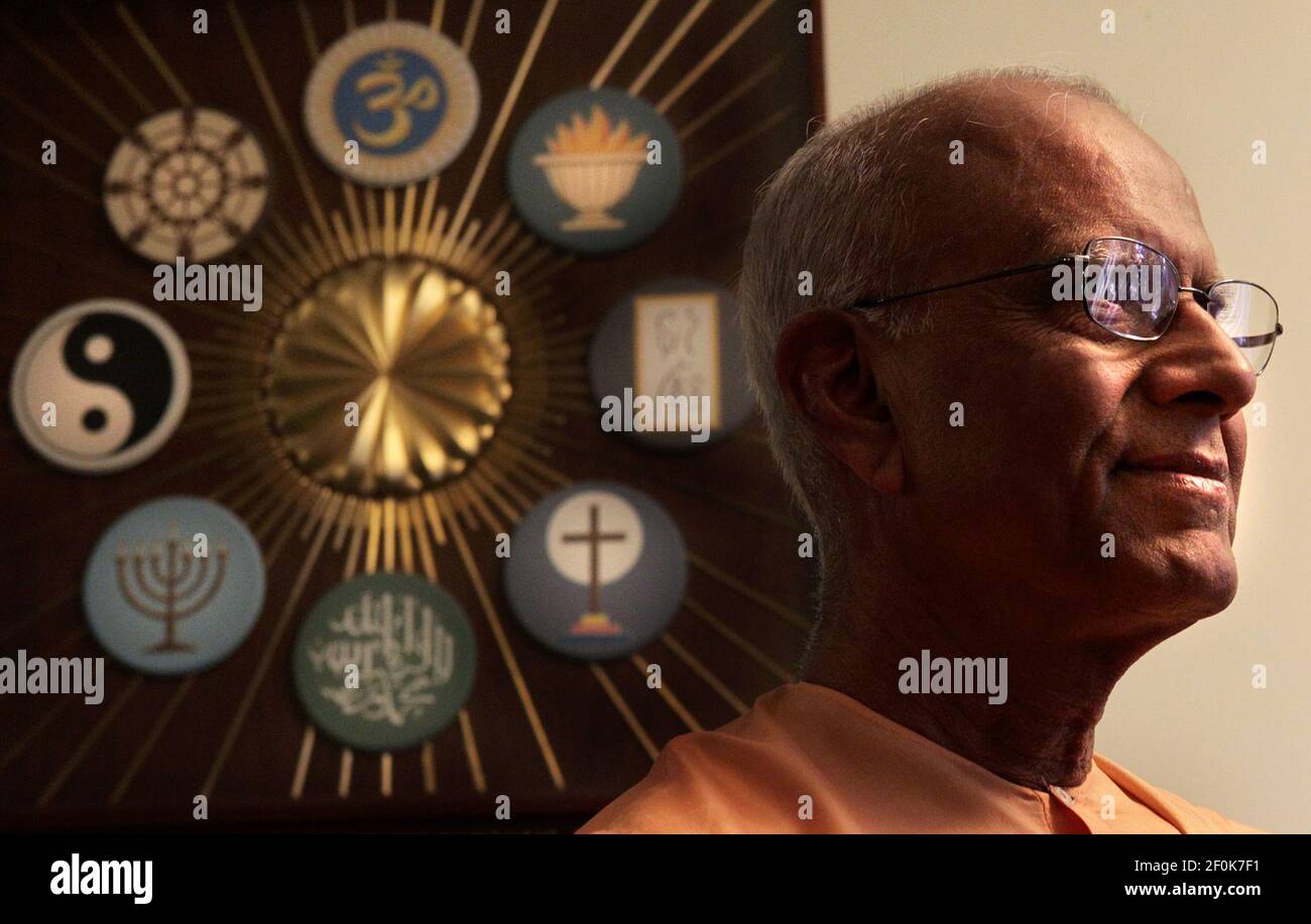 Swami Chetanananda is photographed in front of a plaque depicting ...