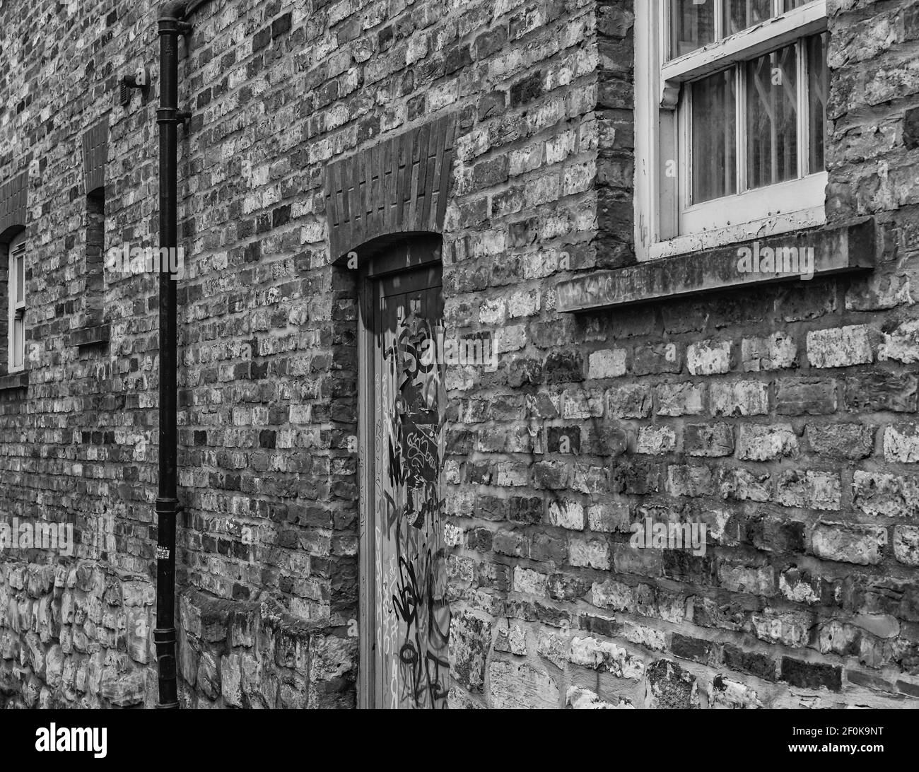 A city alleyway or snicket with an old brick building with a stone base ...