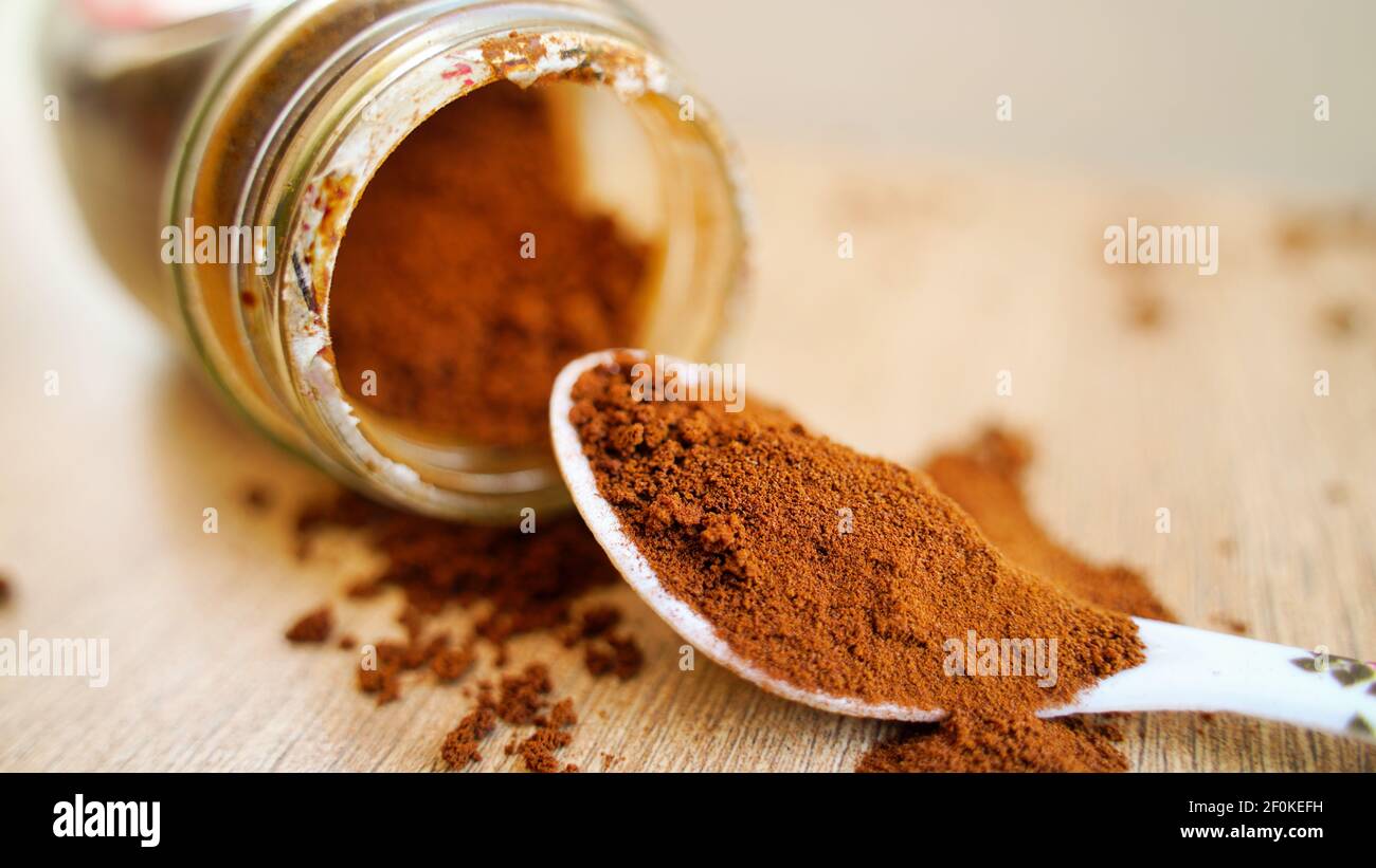 Coffee powder spilling on the wooden table ground with white spoon ...
