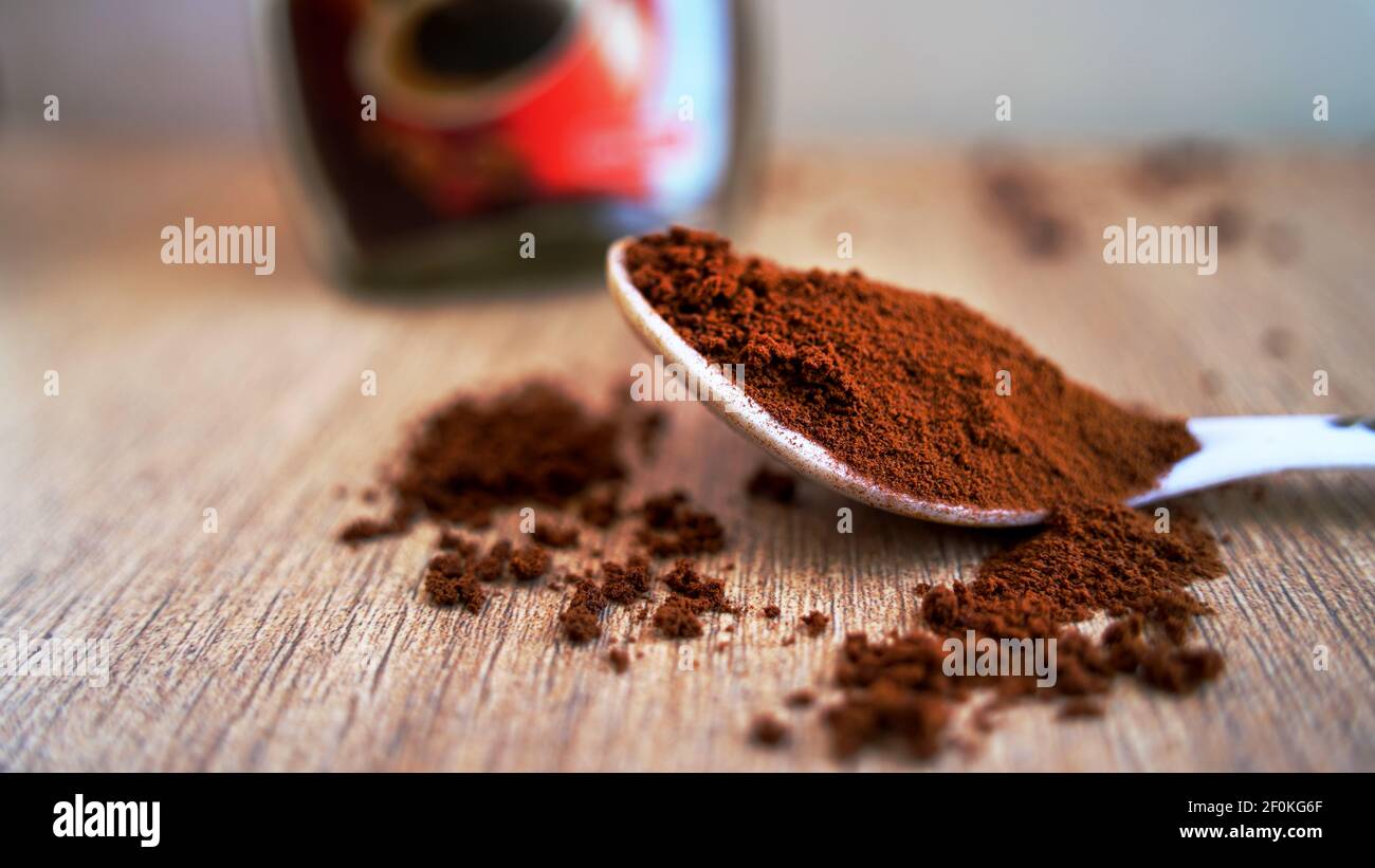 Coffee powder spilling on the wooden table ground with white spoon ...