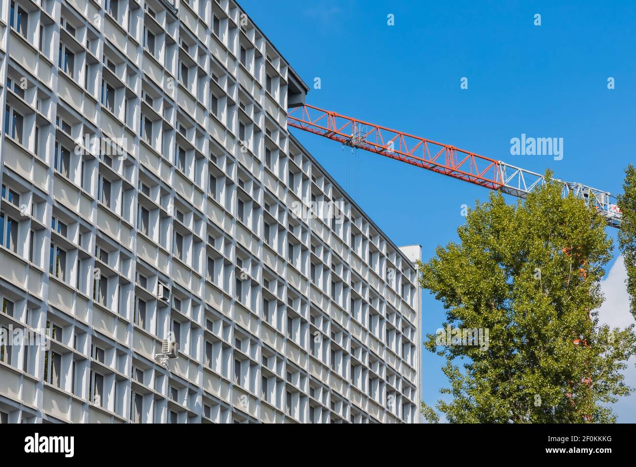 Facade of high corporate building with long red and white crane above ...