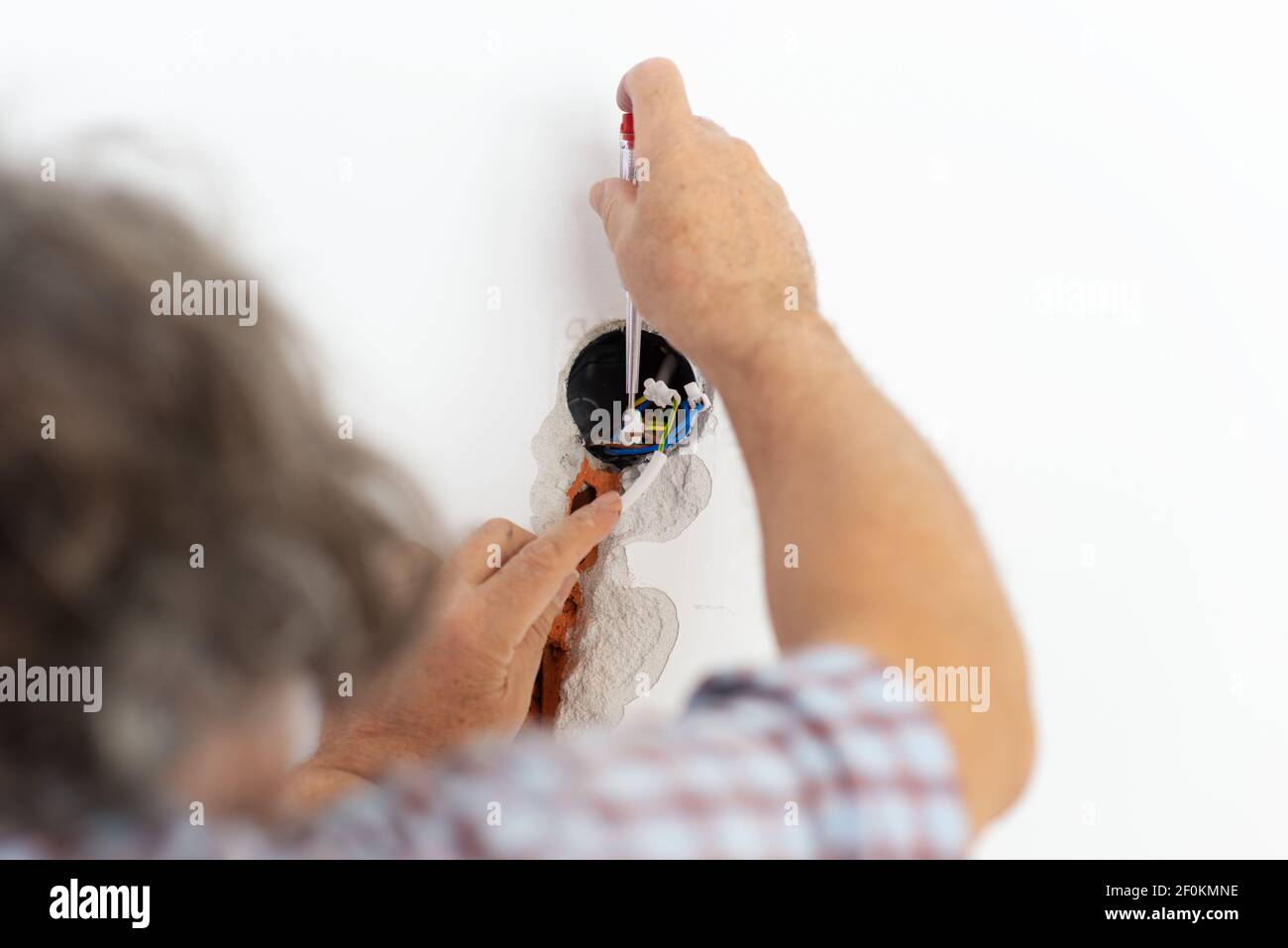 Electrician checking the presence of electrical current in the wires ...