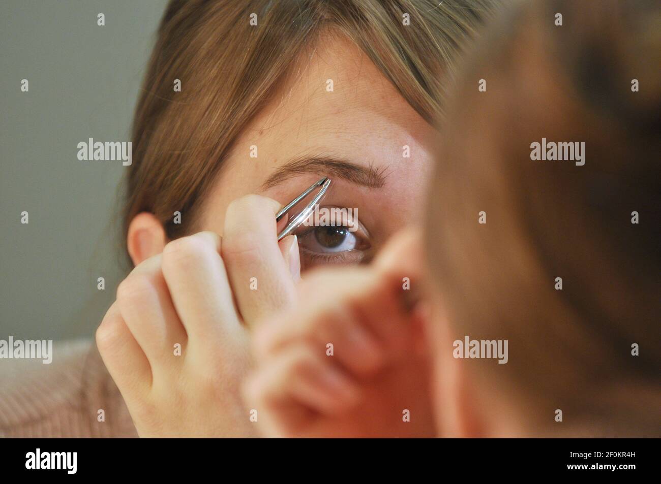 TWEEZING: Then she uses tweezers to remove hairs below the stencil line ...