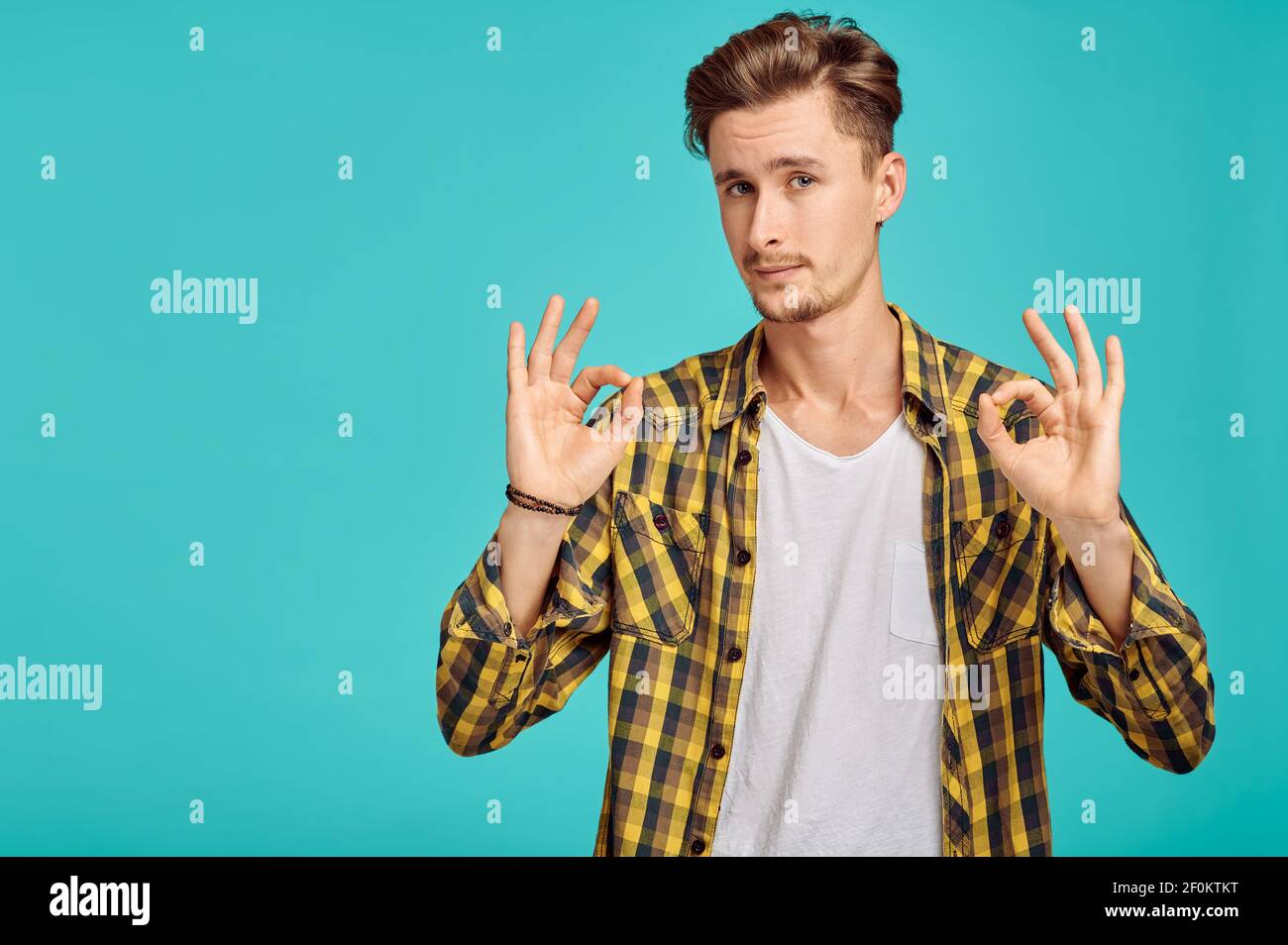 Young man shows Ok sign, blue background, emotion Stock Photo - Alamy