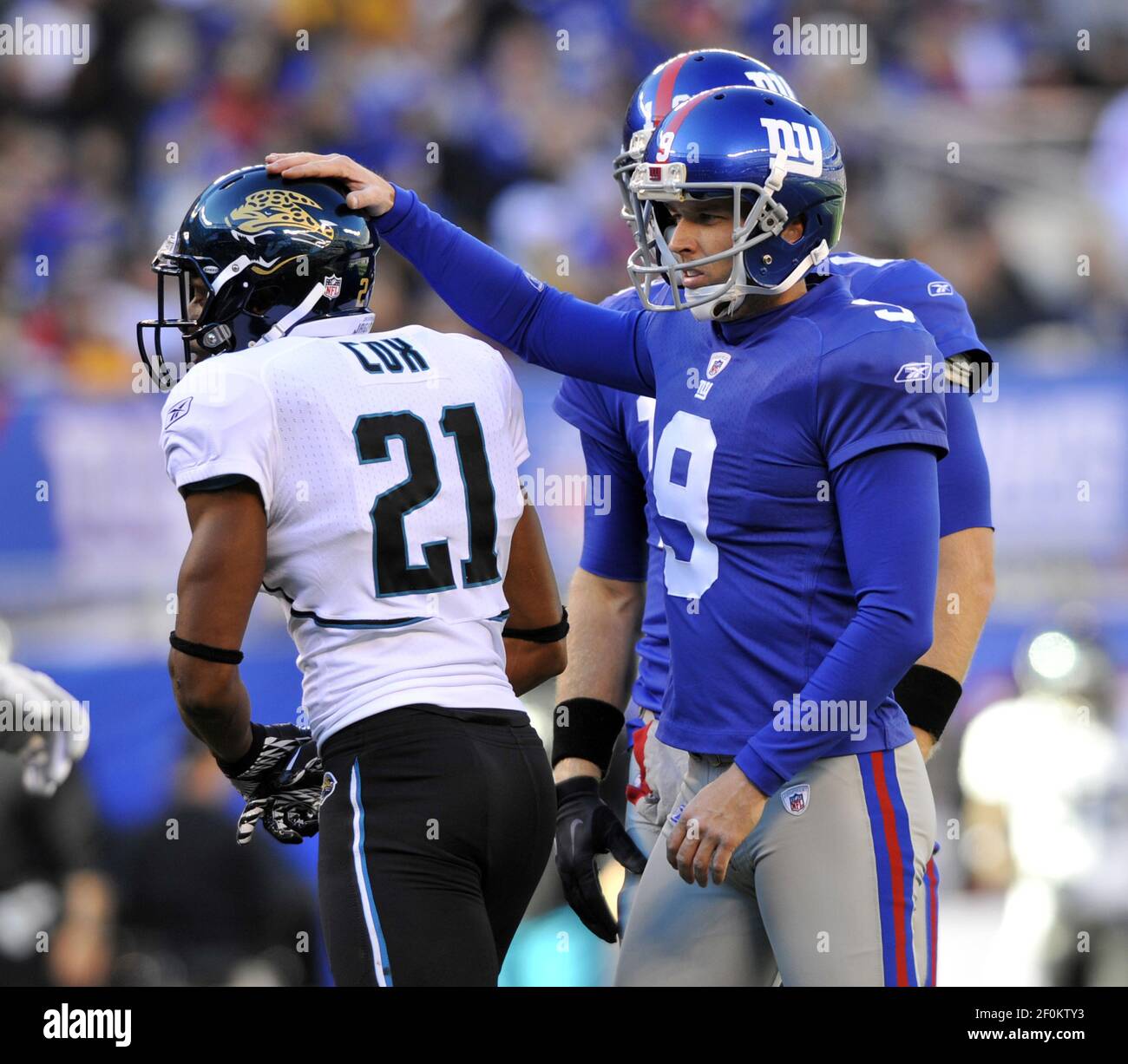 Lawrence Tynes of the New York Giants pats Derek Cox of the ...