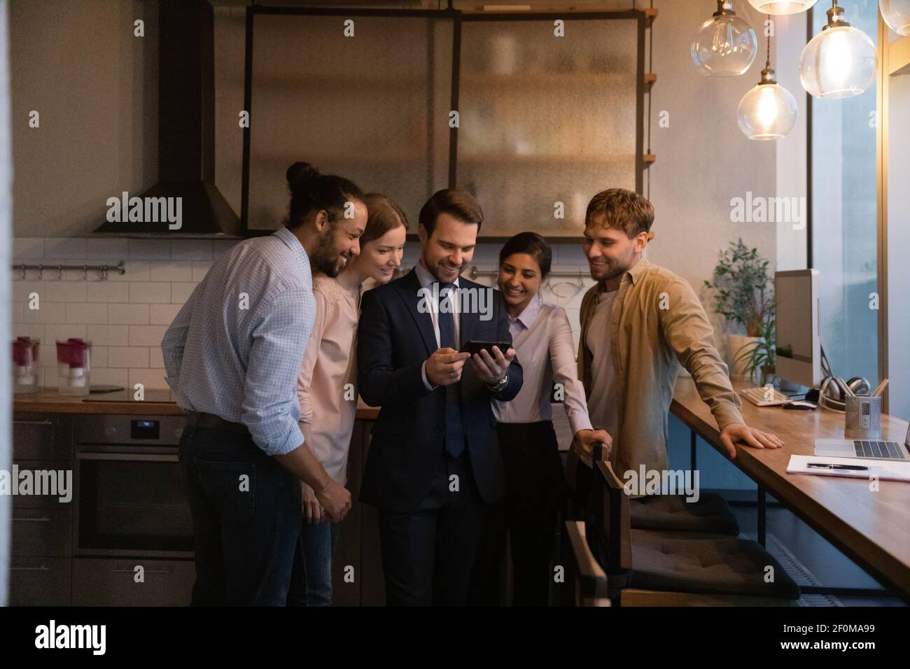 Happy diverse colleagues looking at phone screen together, having fun ...