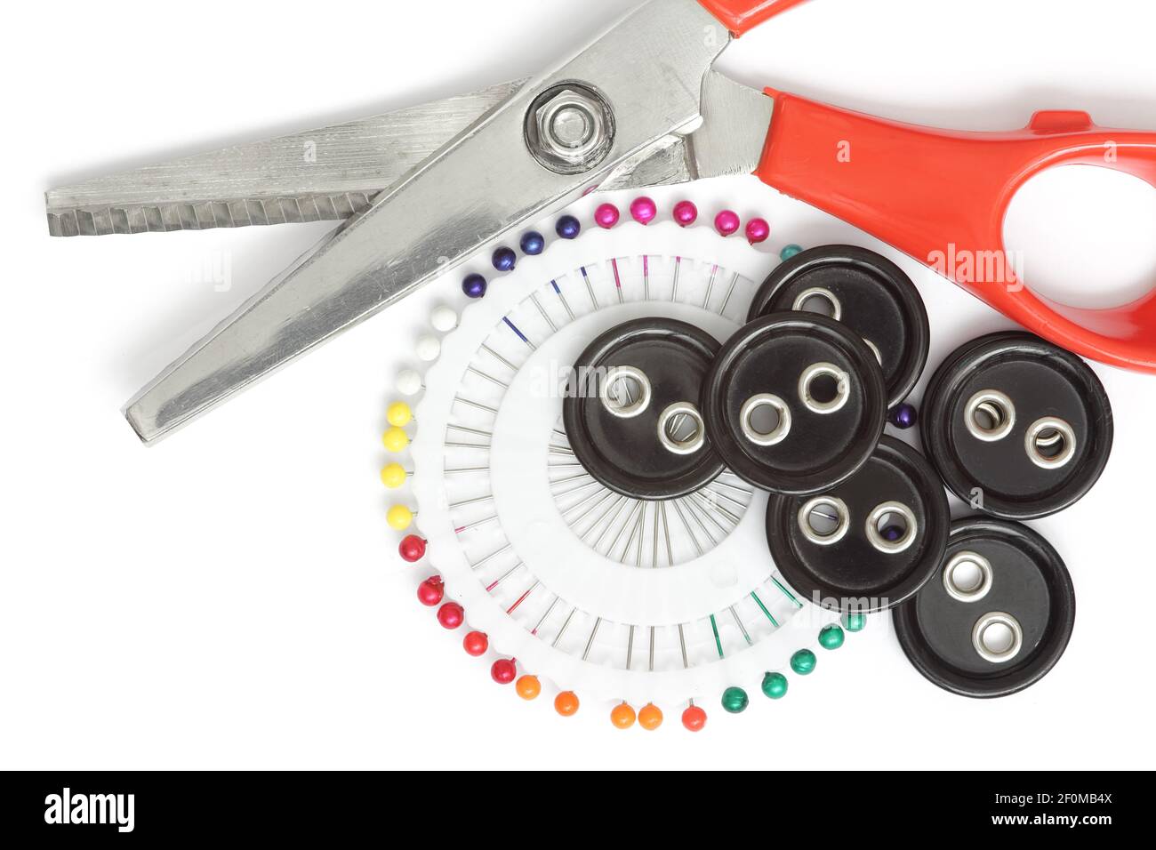 Close-up red pair of scissors with needle and large buttons isolated on ...
