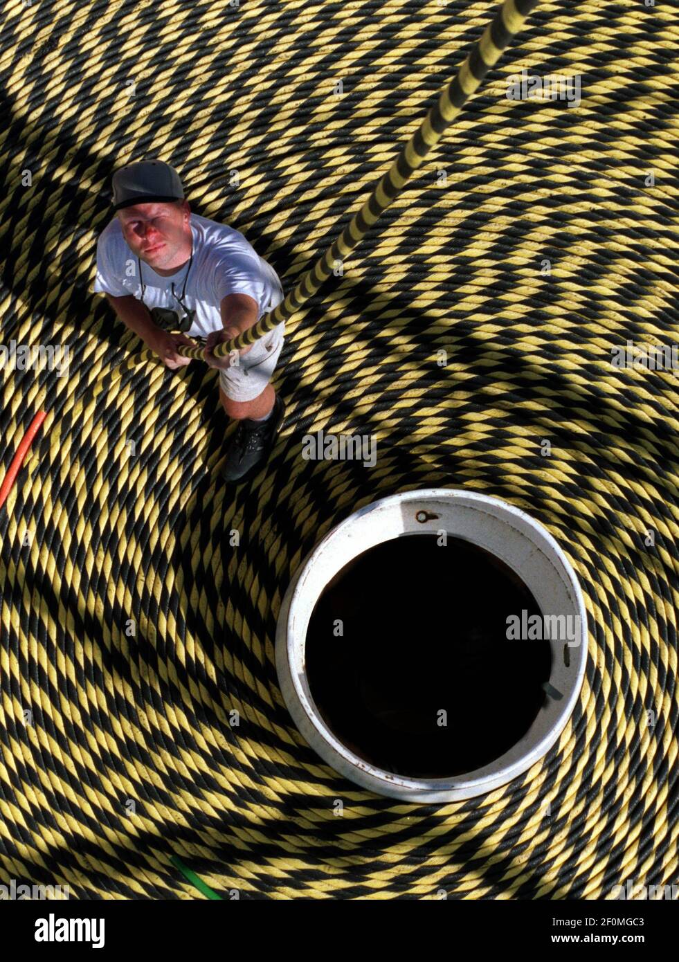 A crewman pulls on undersea cable that will be laid in the Caribbean in ...