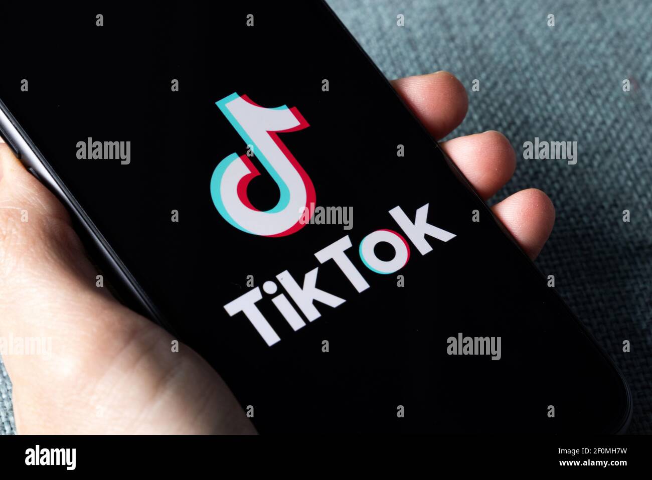 TikTok application icon on Apple iPhone 11 screen close-up. Hand ...