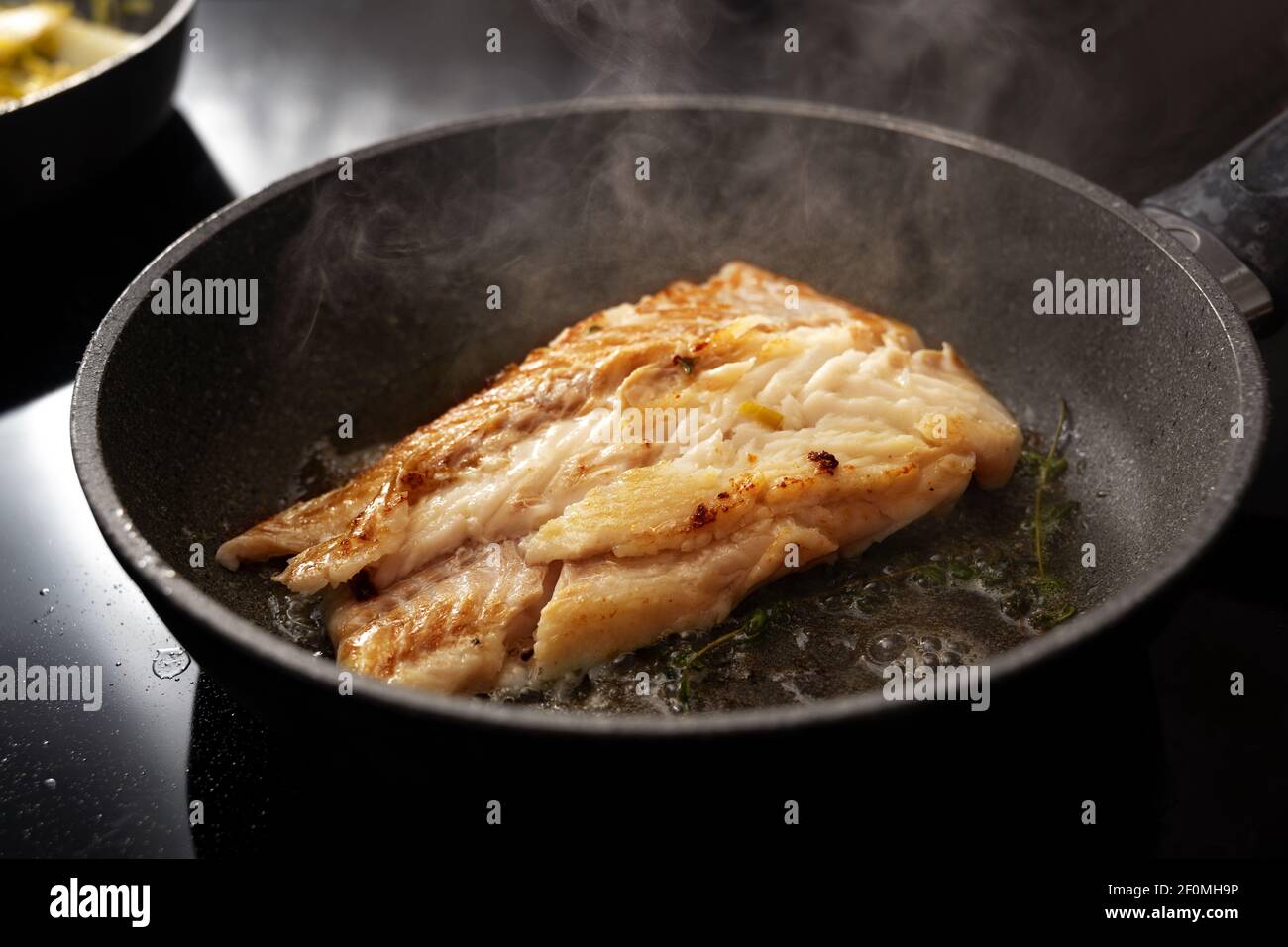 Cod fish fillet sautéed with thyme in a steaming frying pan on the ...