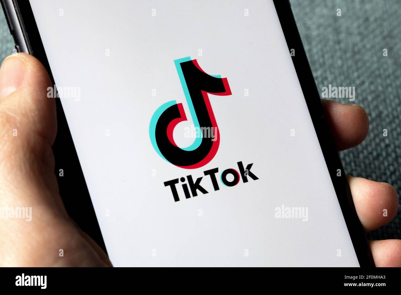 TikTok application icon on Apple iPhone 11 screen close-up. Hand ...