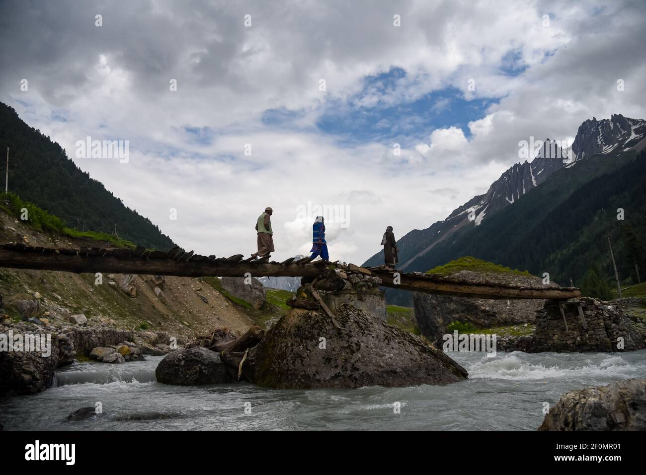 Residents cross a wooden bridge during a cloudy evening in Sonamarg ...
