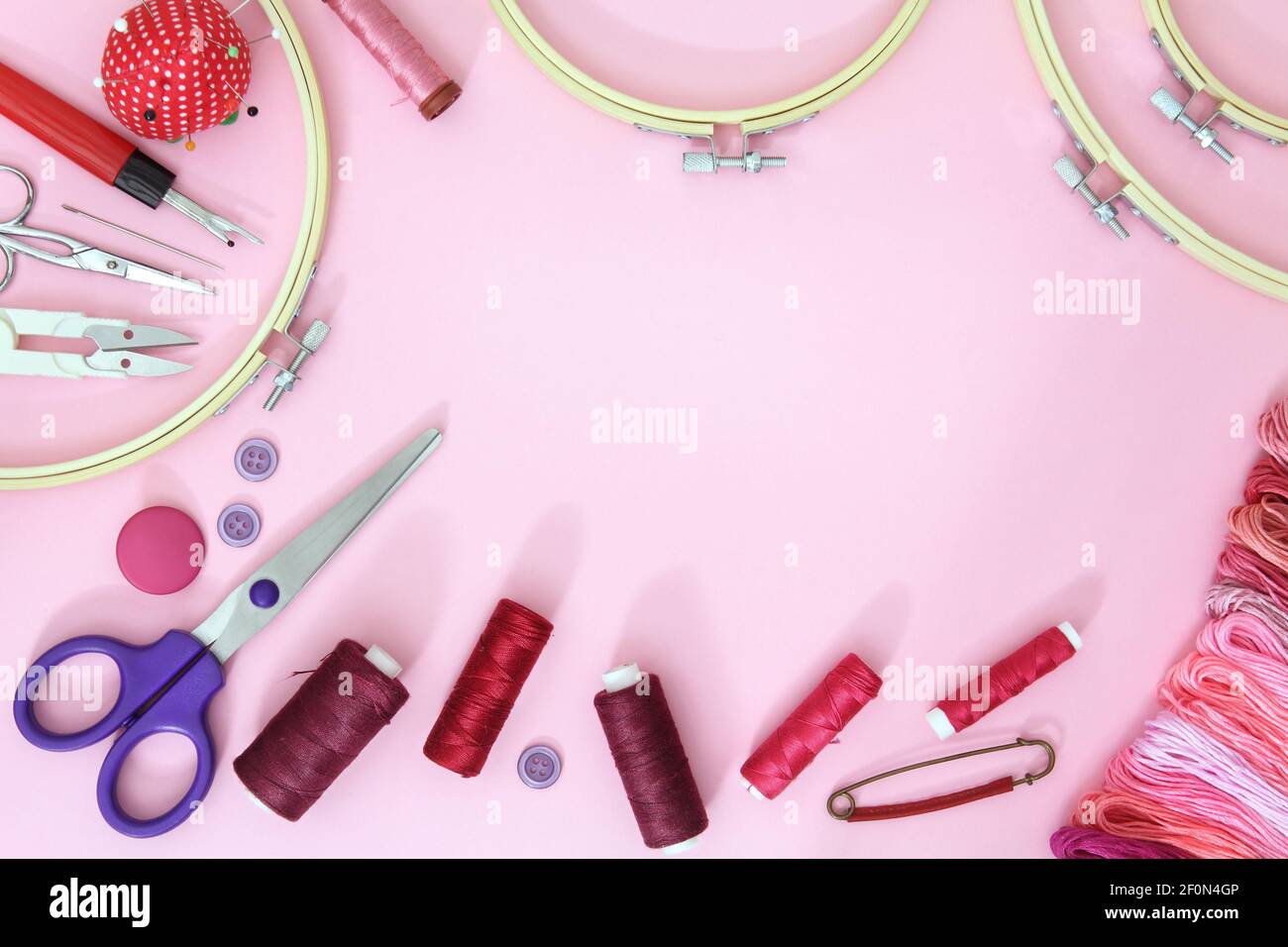 Sewing accessories on a pink background with needles, spool of thread ...