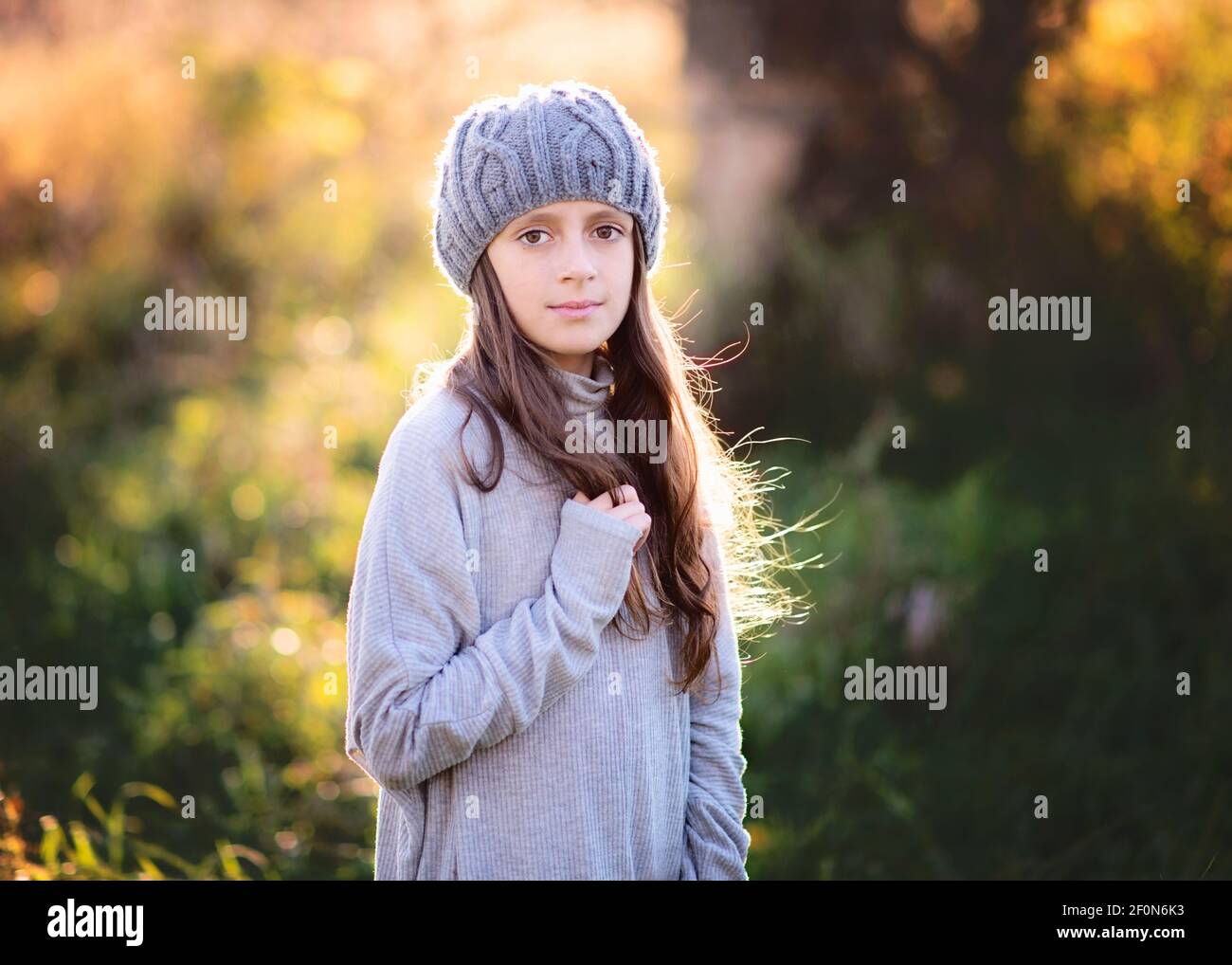 Beautiful young tween girl in sweater and hat outdoors in the fall ...