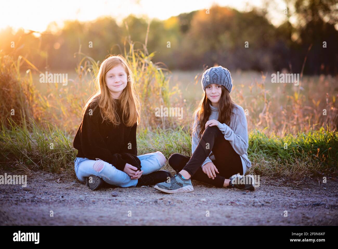 Two beautiful young tween girls sitting outdoors in fall, backlit Stock ...