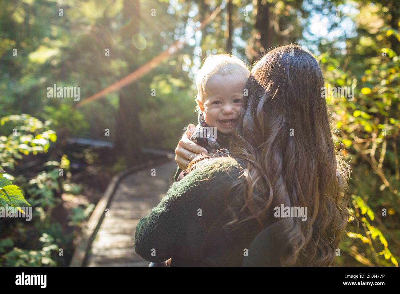 Happy boy looking over mothers shoulder Stock Photo - Alamy