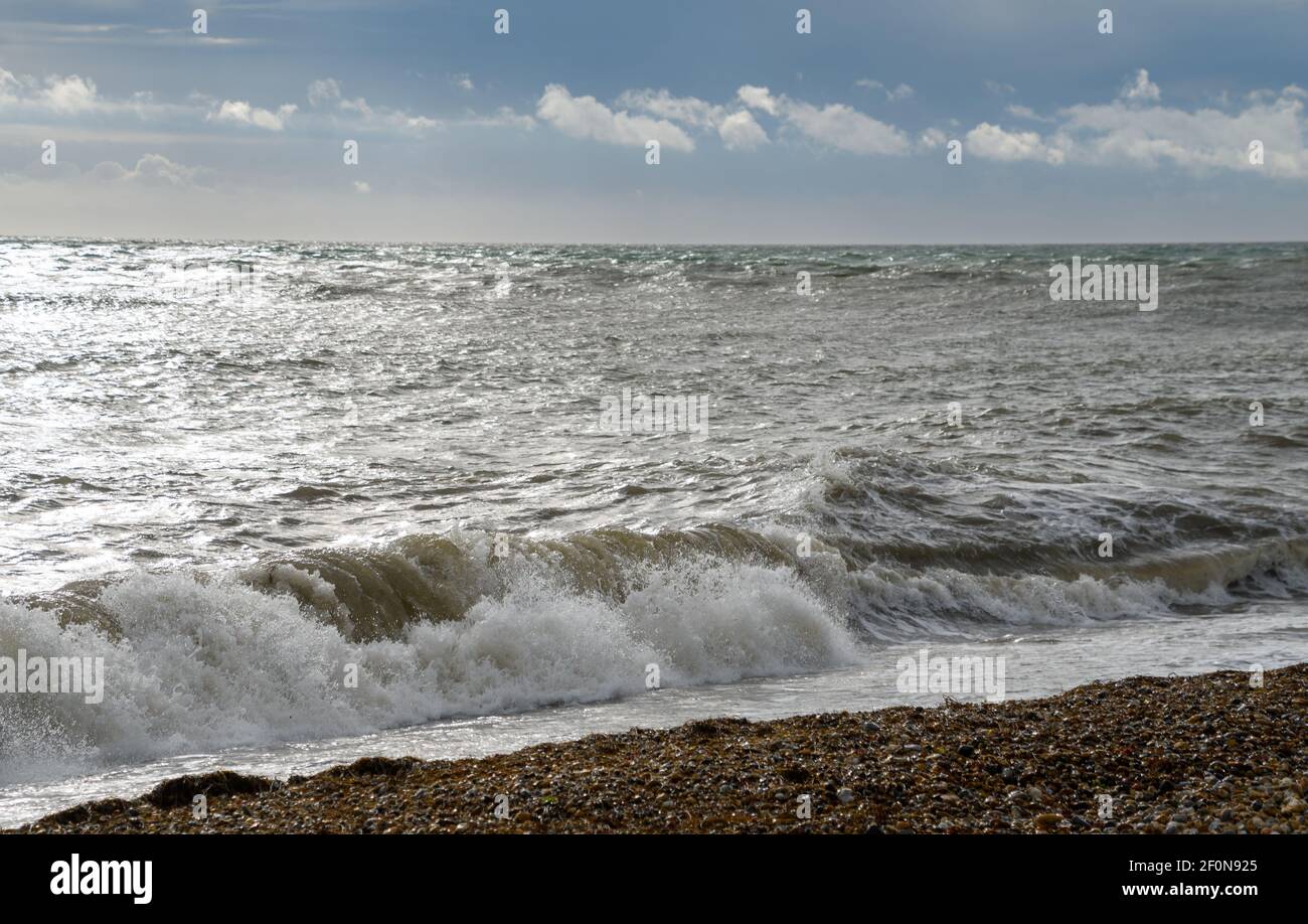 Waves from the English Channel breaking onto the stony beach of Selsey ...