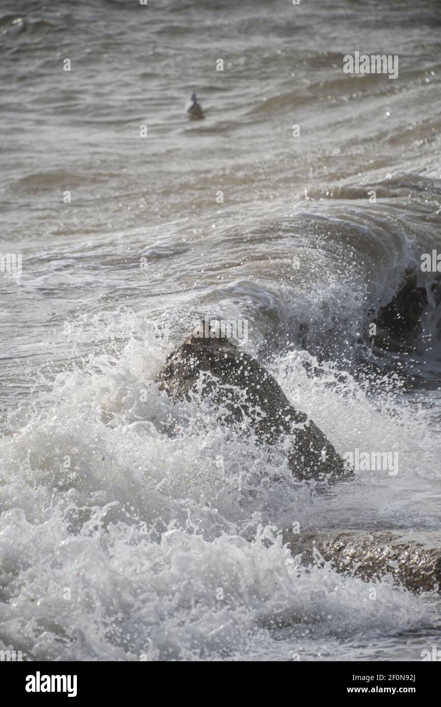Waves from the English Channel breaking against a rock on a beach in ...