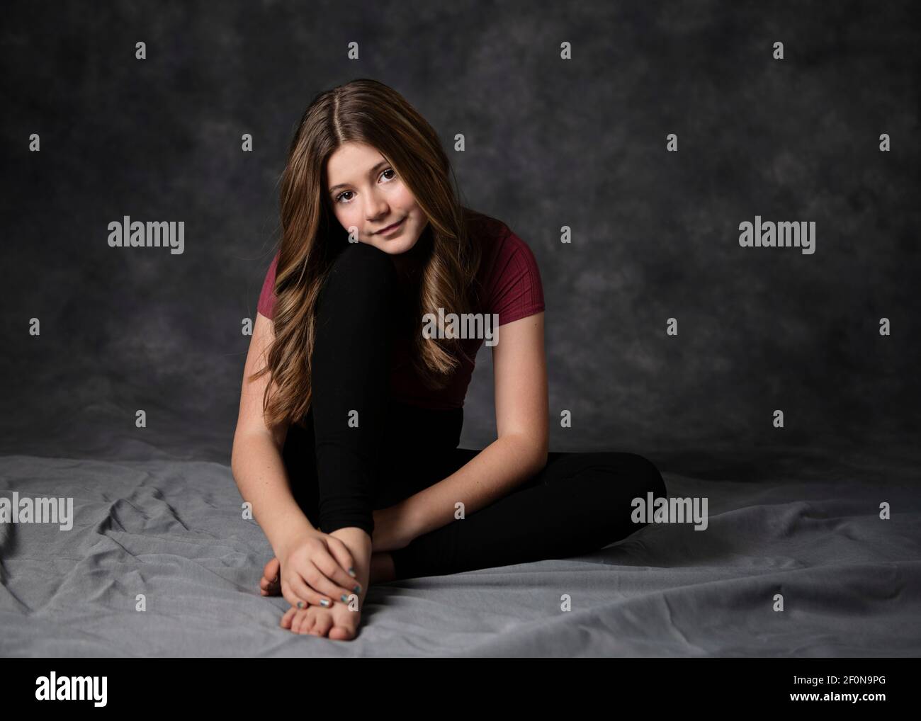 Beautiful tween girl sitting on floor, low key Stock Photo - Alamy