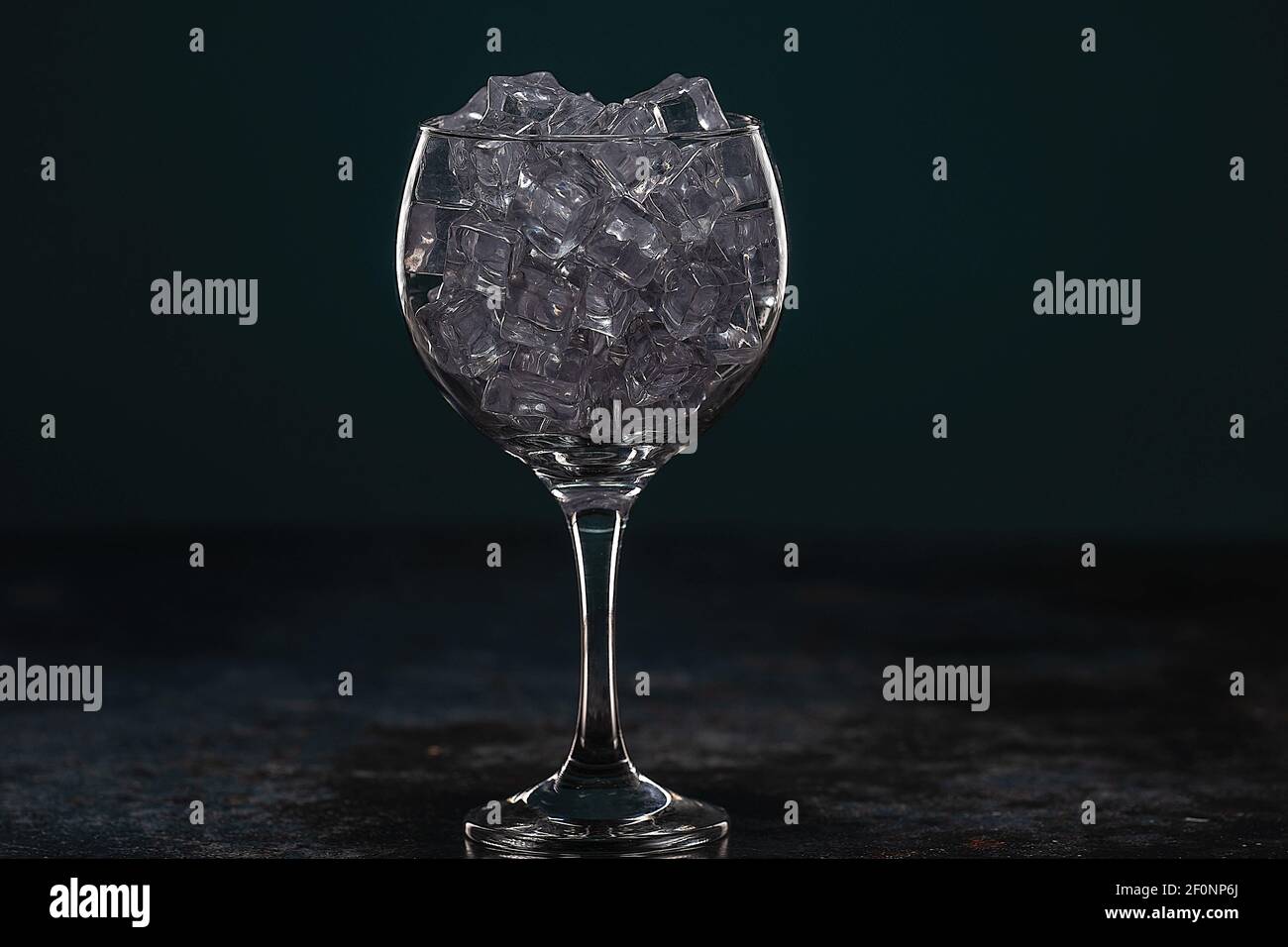 Glass full of ice standing on a table in the dark Stock Photo - Alamy