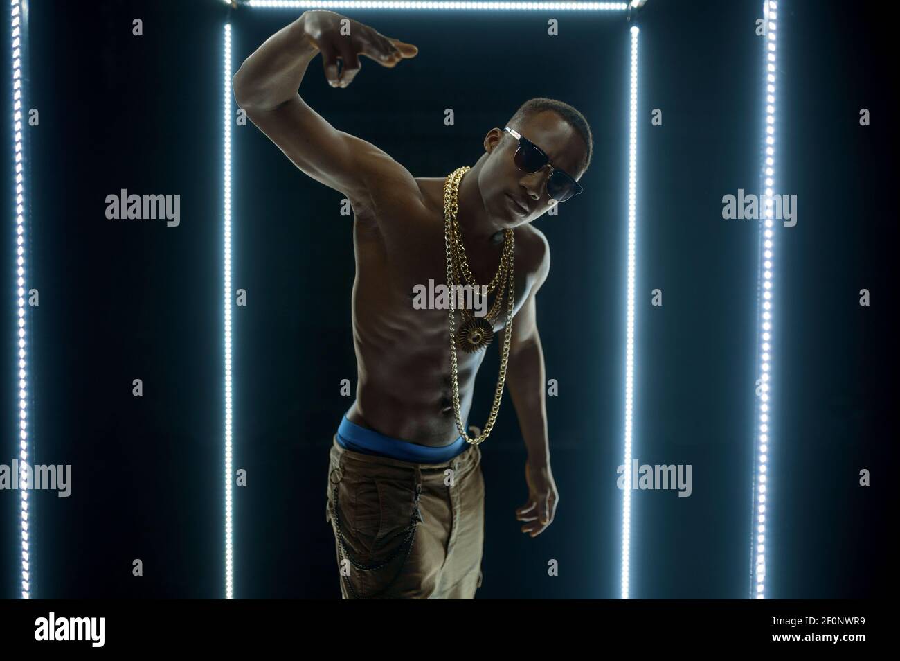 Rapper in gold chains dancing in illuminated cube Stock Photo - Alamy