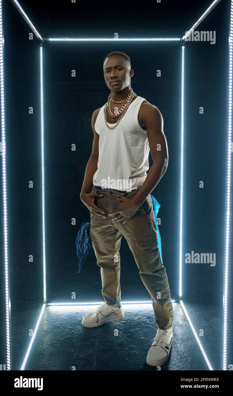 Rapper in gold jewelry poses in illuminated cube Stock Photo - Alamy