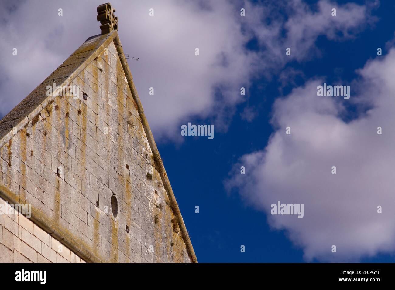 Close-up of a triangular stone wall with a cross on the top against a ...