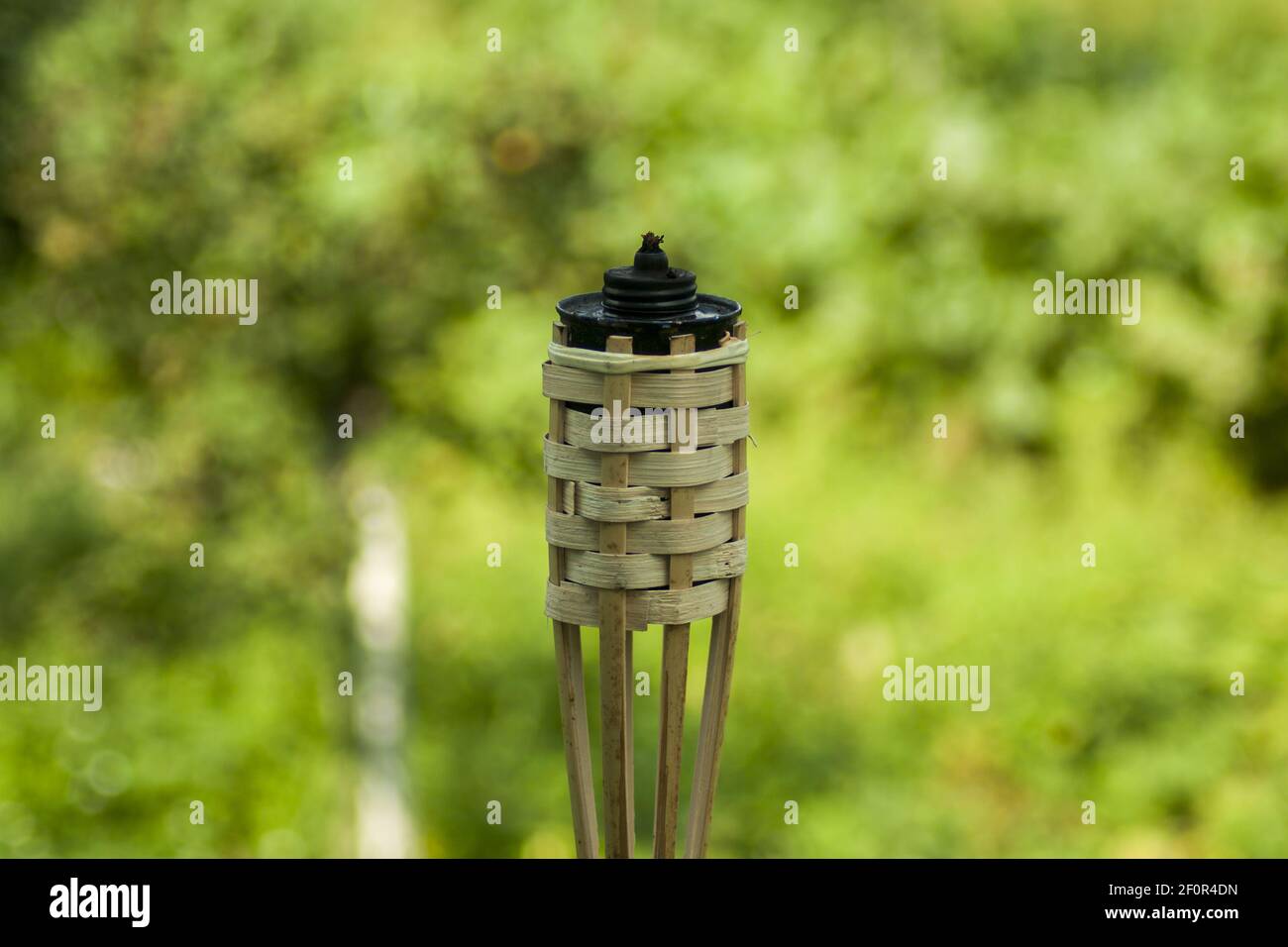 A garden torch standing in the garden. In the background greenery ...