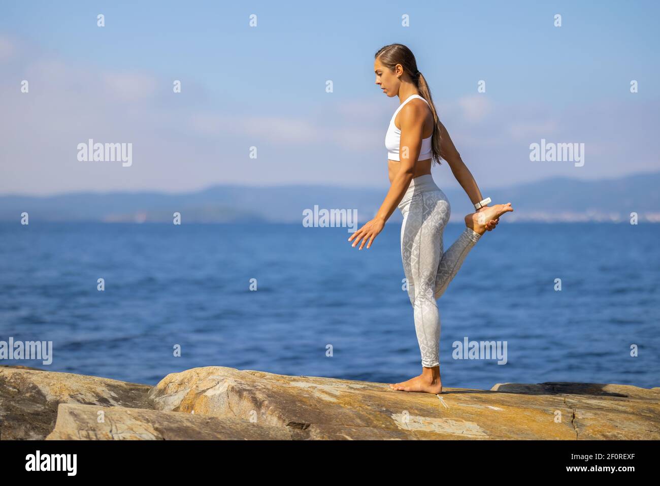 Slim Athletic Woman In Yoga Pose On Rock Stock Photo - Alamy