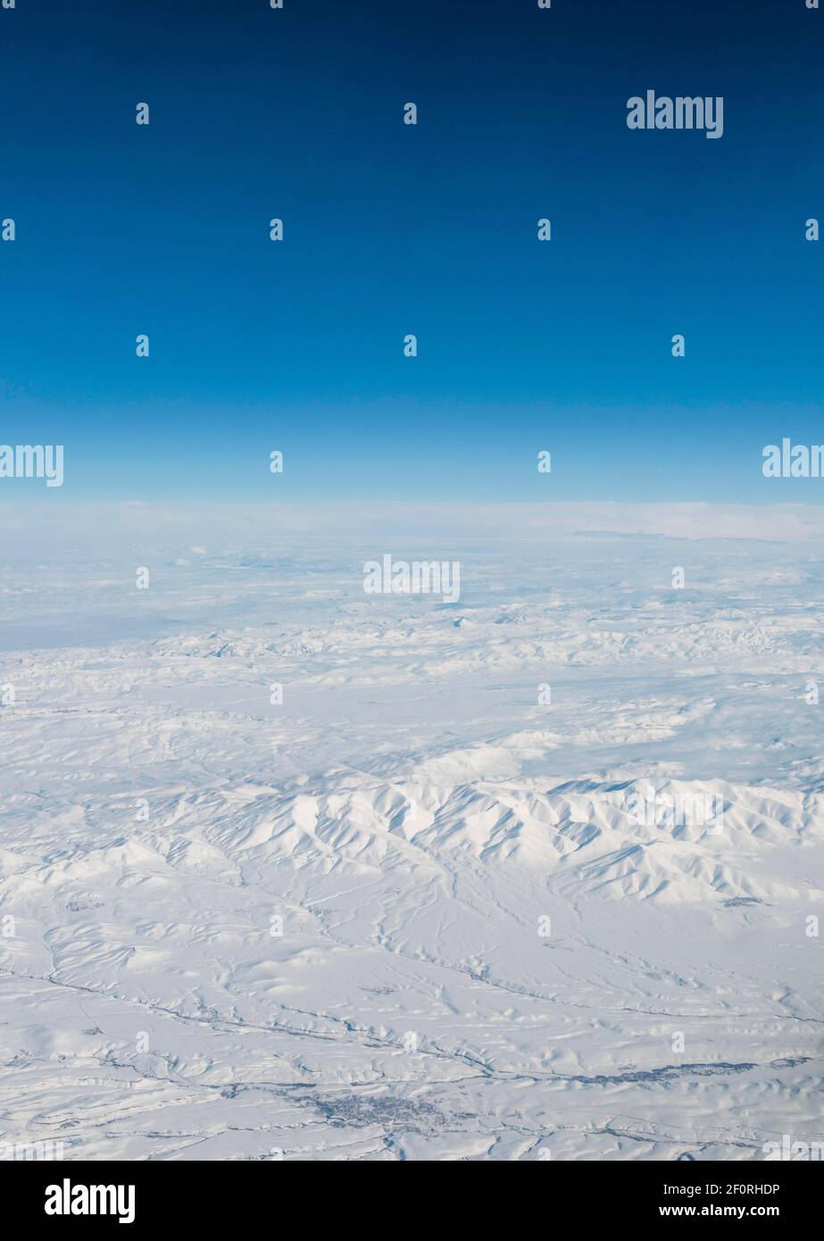 View of mountains and snowy landscape from the airplane, airplane wing ...