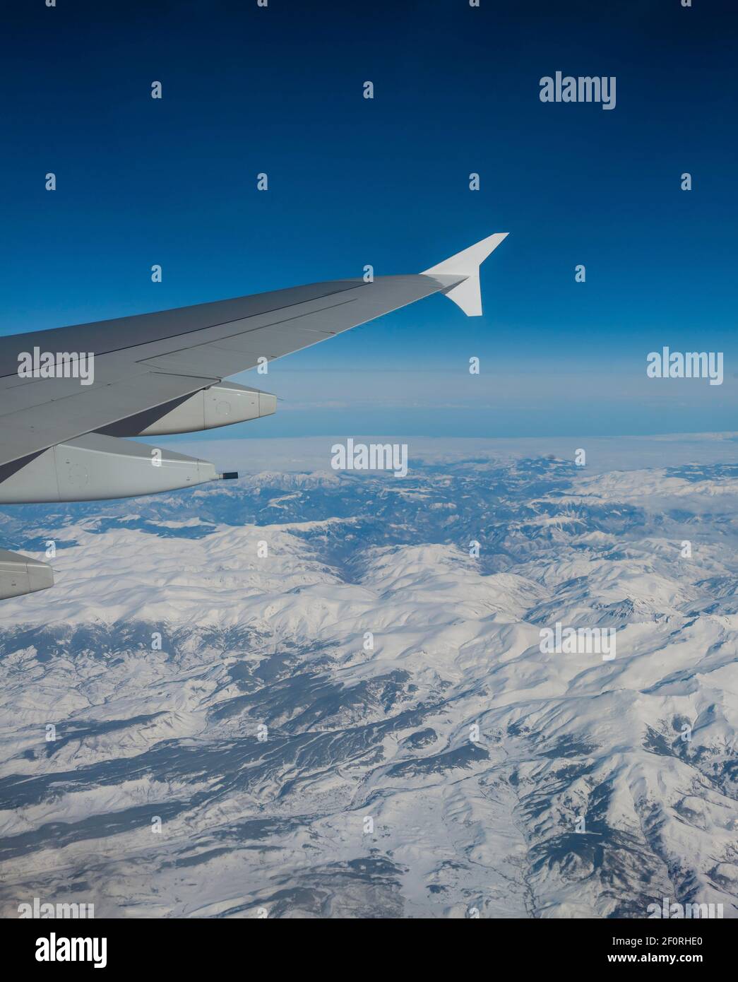 View of mountains and snowy landscape from the airplane, airplane wing ...