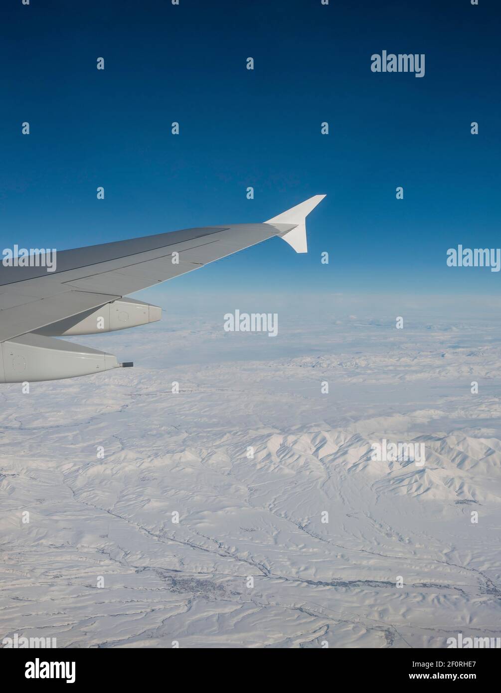 View of mountains and snowy landscape from the airplane, airplane wing ...