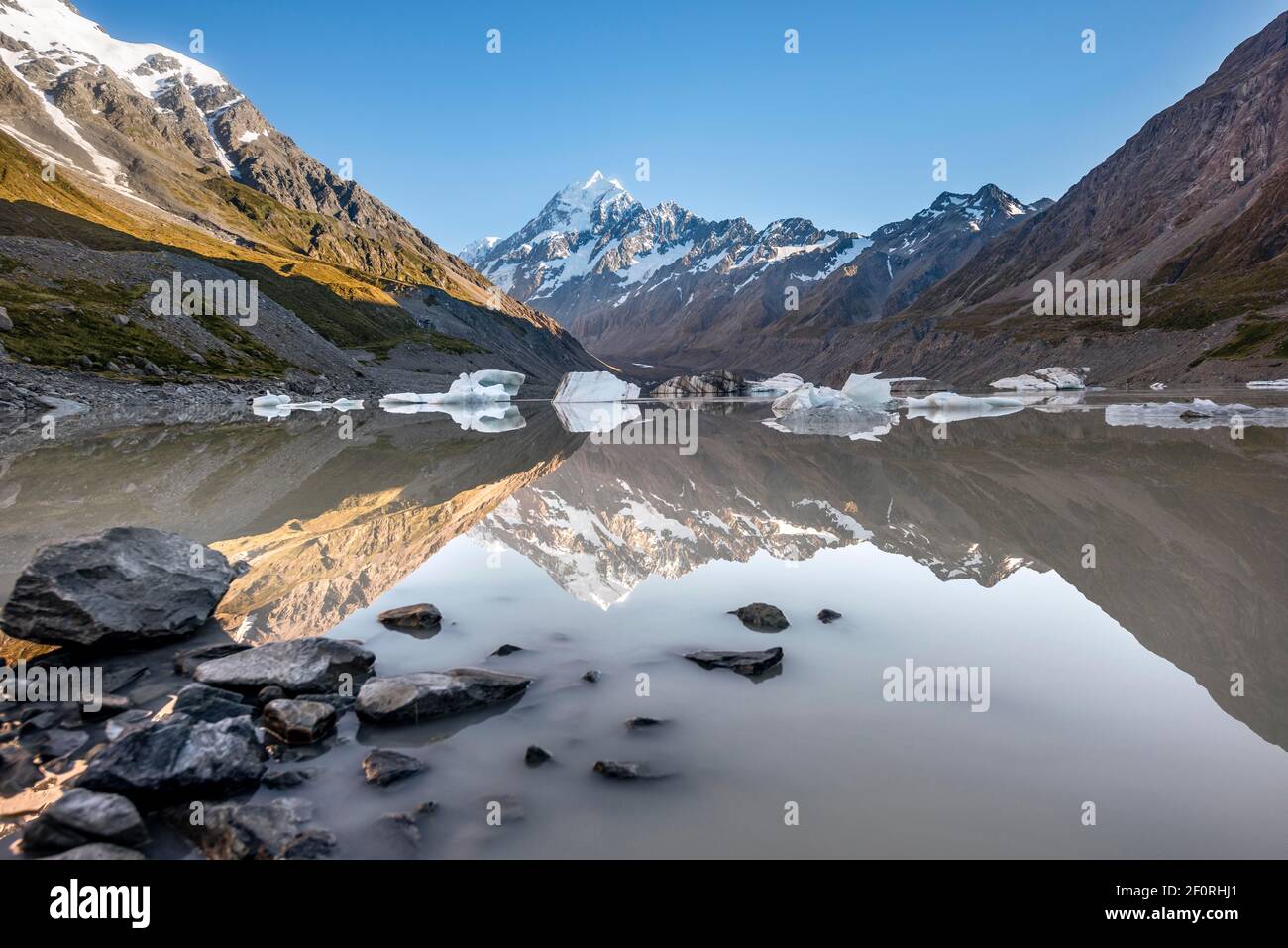 Shore with rocks, reflection in Hooker Lake at sunrise, Mount Cook in ...